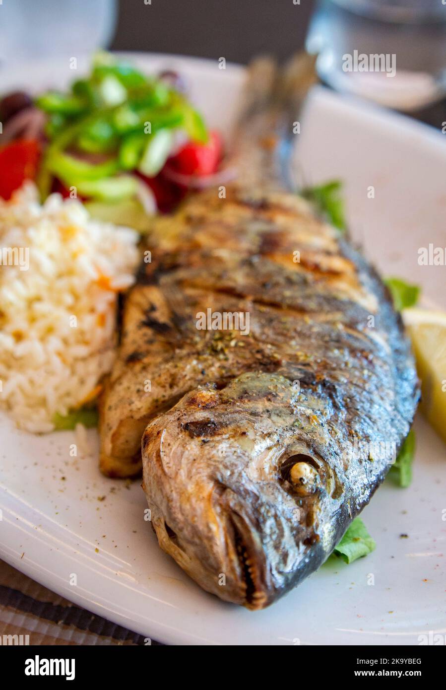 A whole grilled sea bream with rice and salad from a Greece local ...