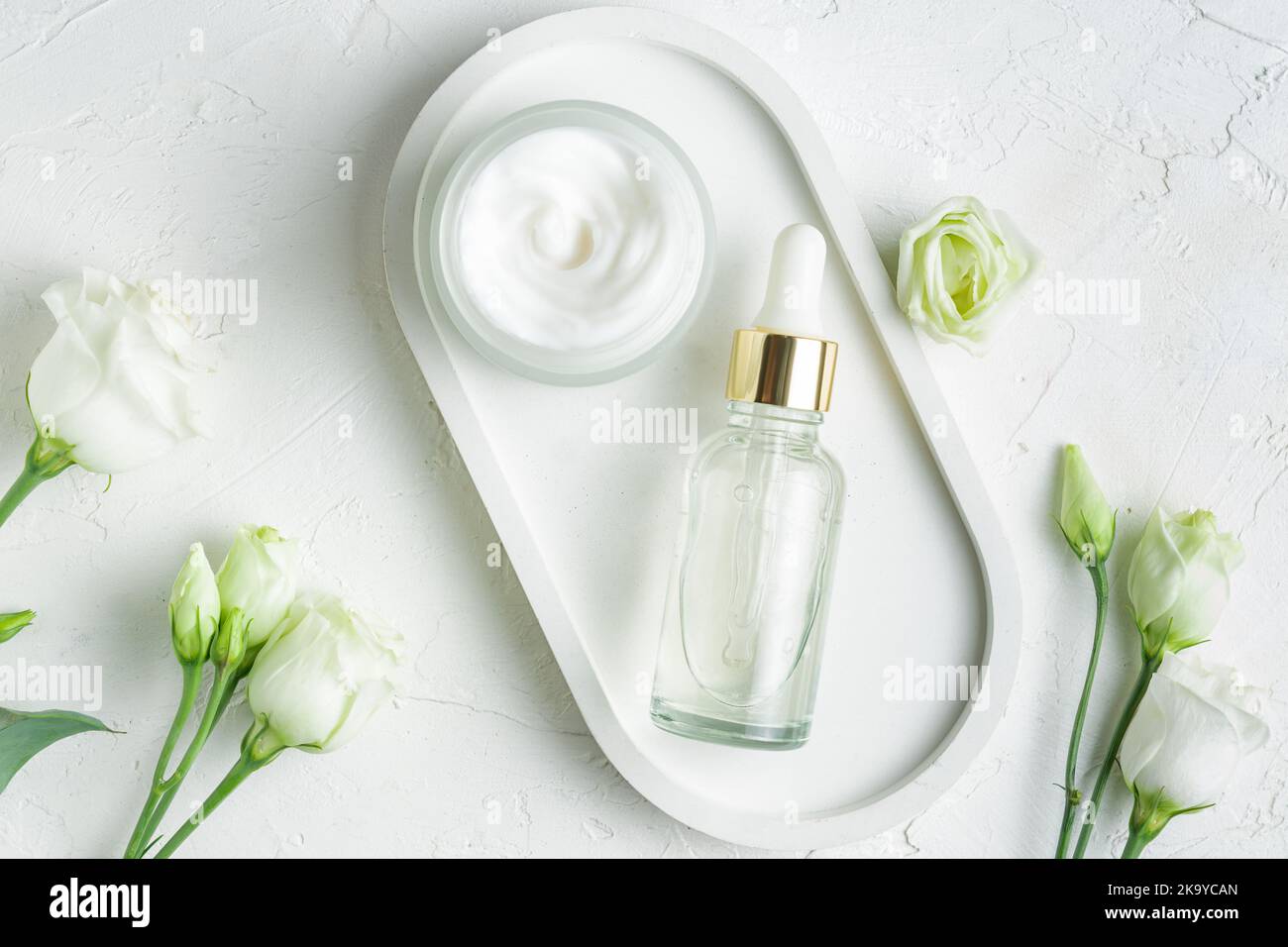 cosmetic bottle containers with blooming eustoma flowers on concrete ...