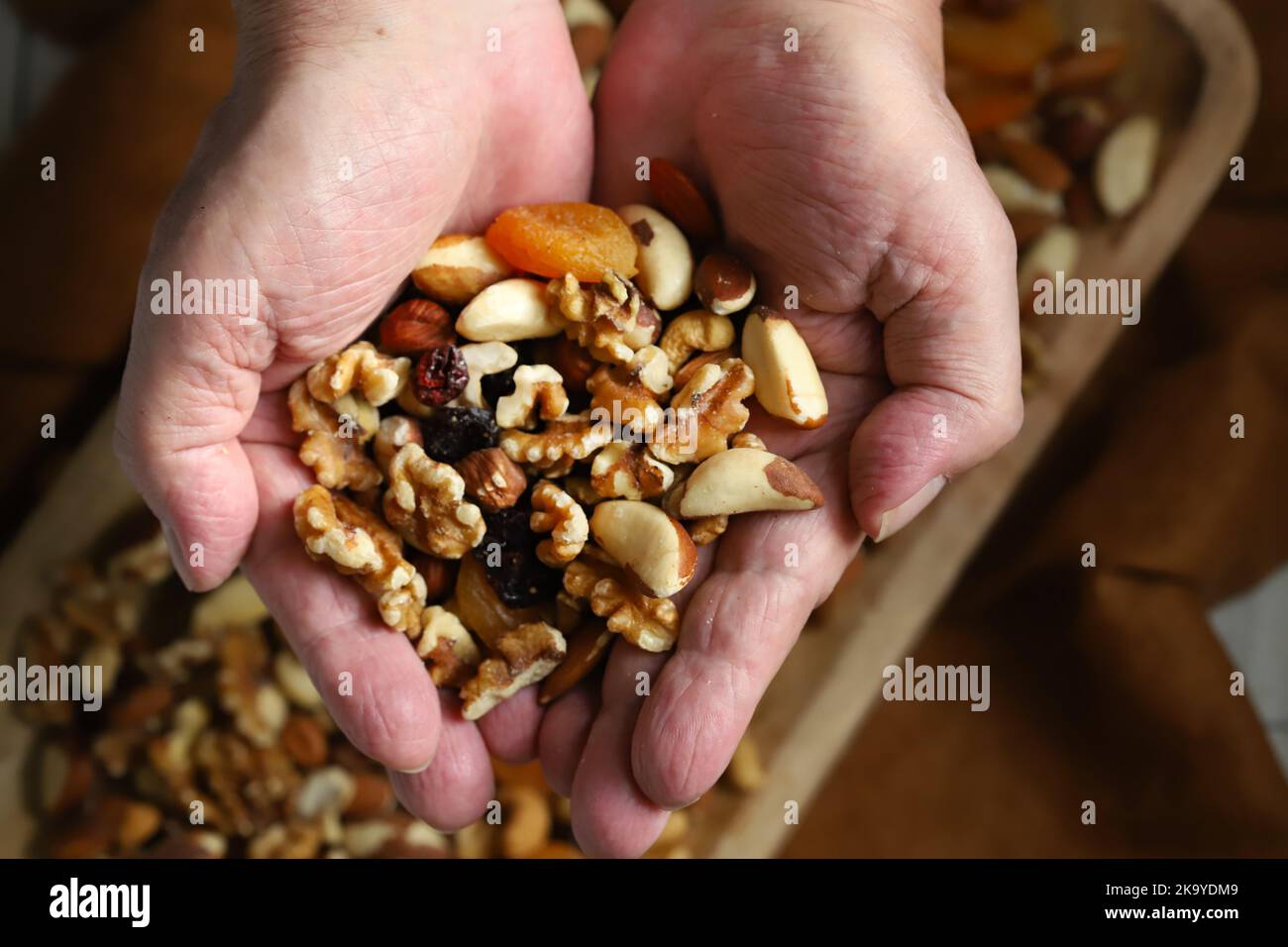 A handful of nuts and dried fruits in male palms. Healthy sweets or ...