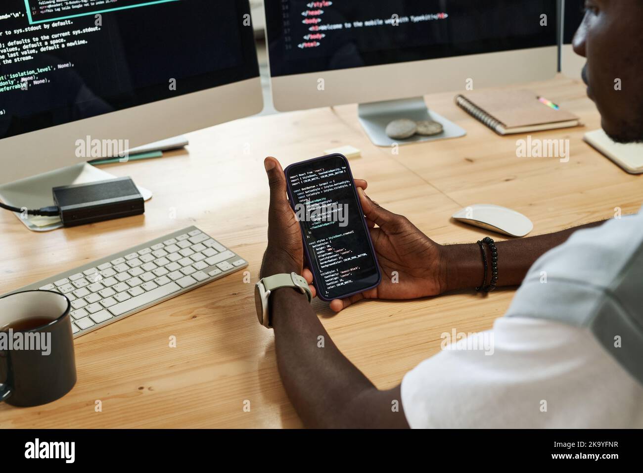 Hands of young black man scrolling through codes in smartphone while ...