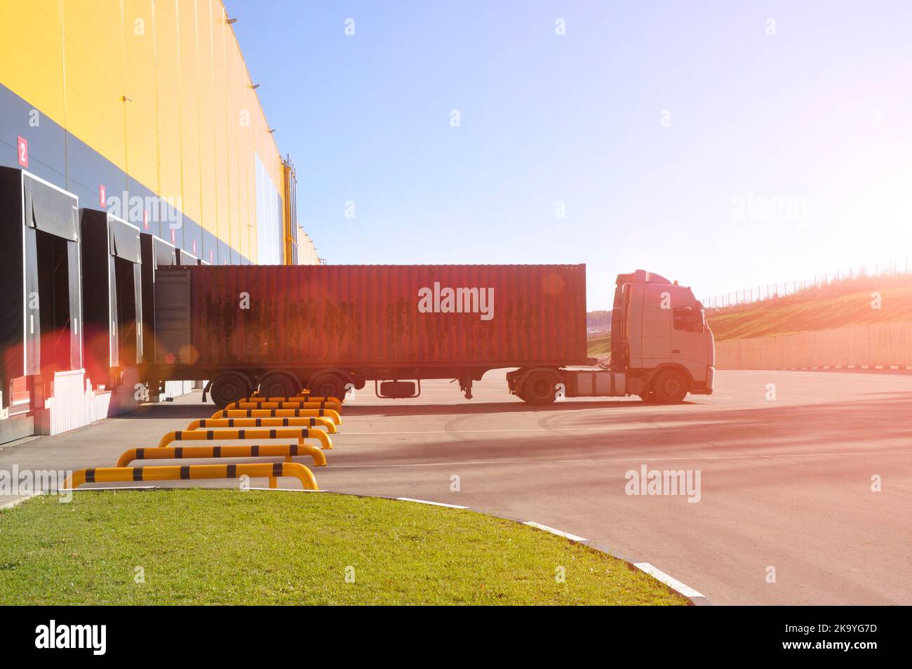 Unloading trucks in a modern warehouse complex at sunset Stock Photo ...