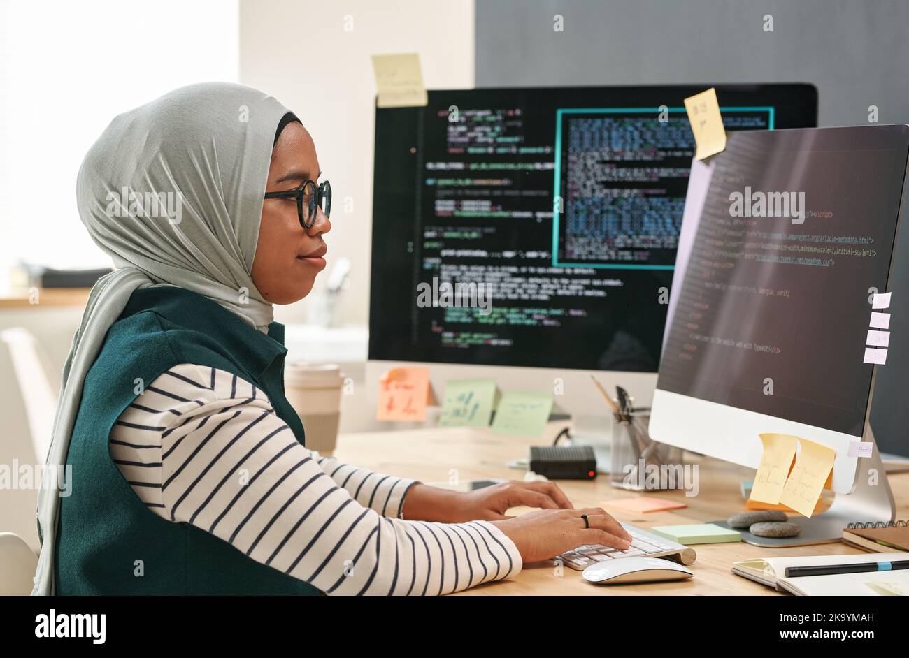 Young Muslim businesswoman in hijab looking at computer screen while ...