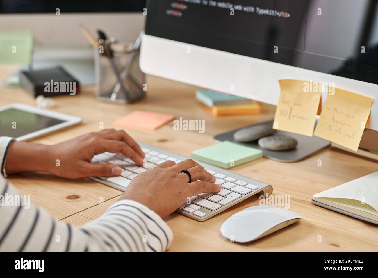 Hands of young woman pressing keys of keyboard while sitting in front ...