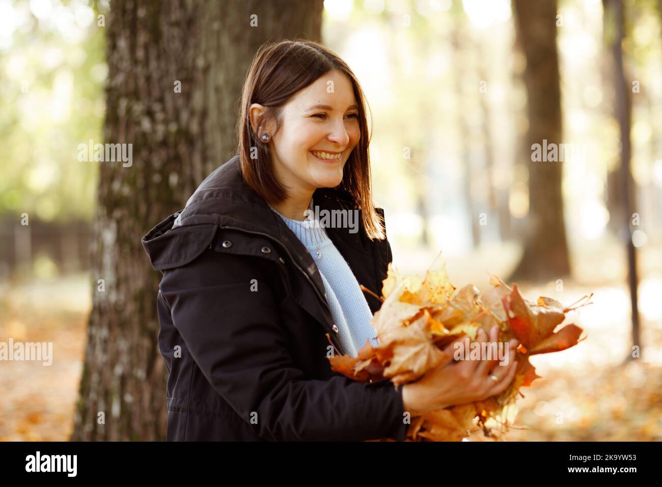 Horizontal portrait of smiling woman in black jacket throwing up ...