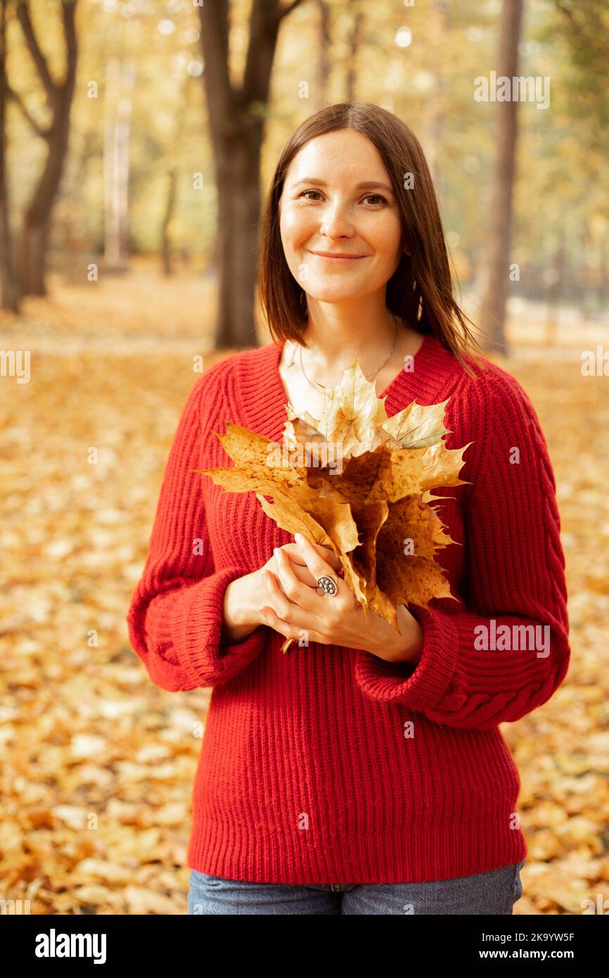 Portrait of joyful pretty woman in cozy red knitted sweater holding ...