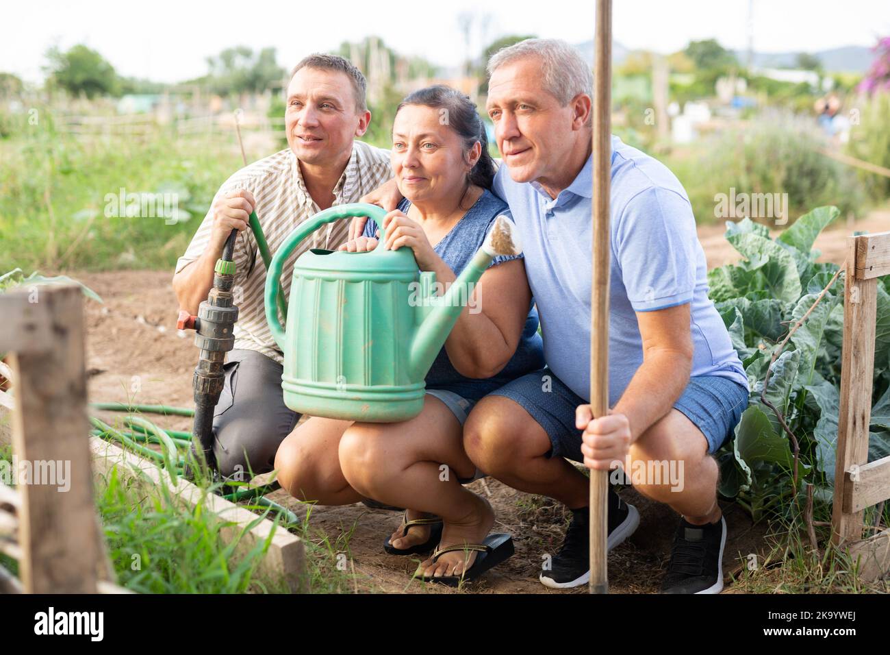 Portrait of happy farmers with gardening tools in garden after work ...