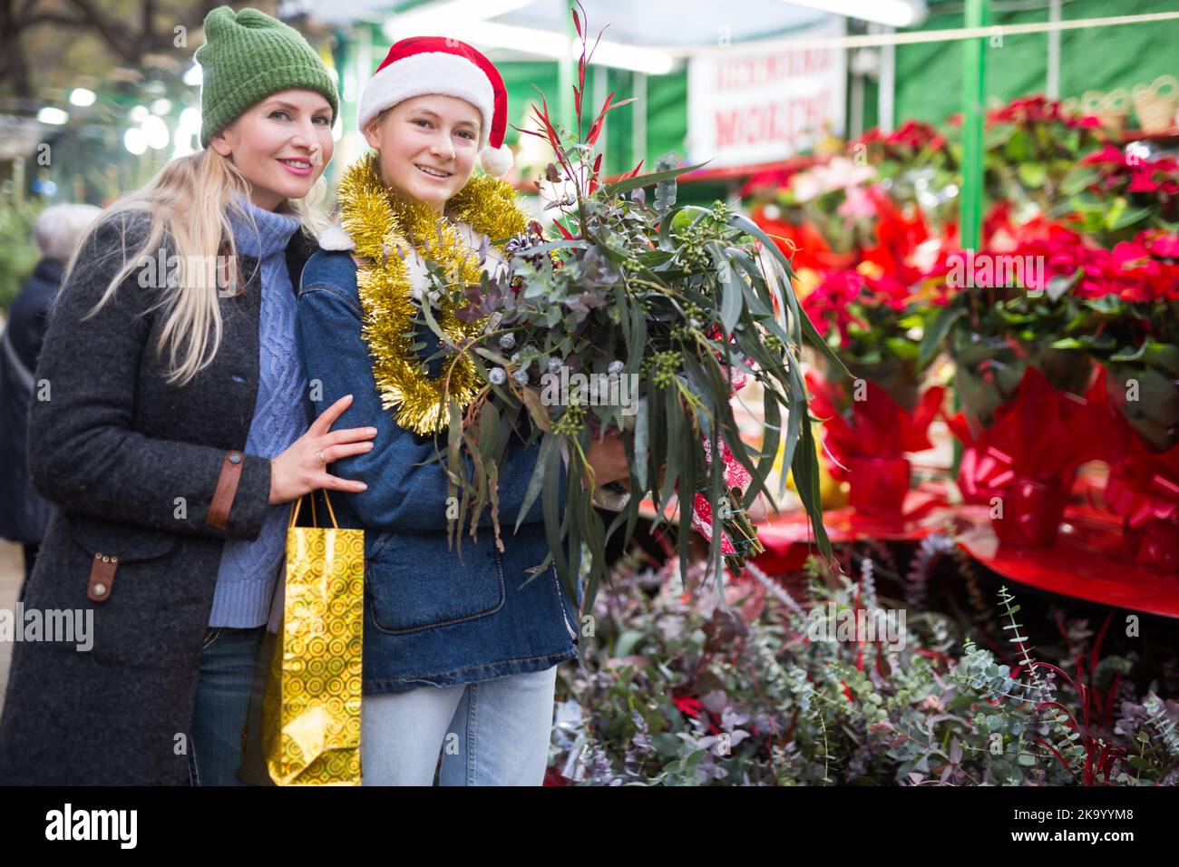 Portrait of woman and her teenage daughter choosing Christmas bouquet ...