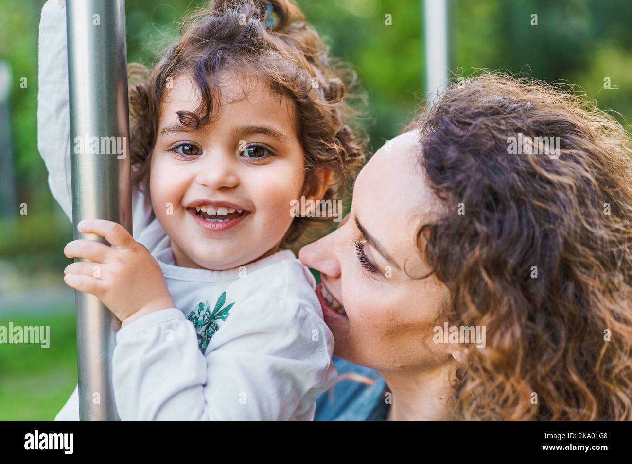 Happy caucasian little child girl having fun climbs on the pole when ...