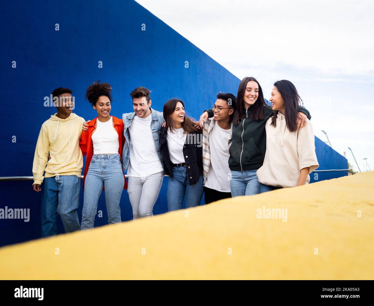 Group of multiethnic young friends walking through the city laughing ...