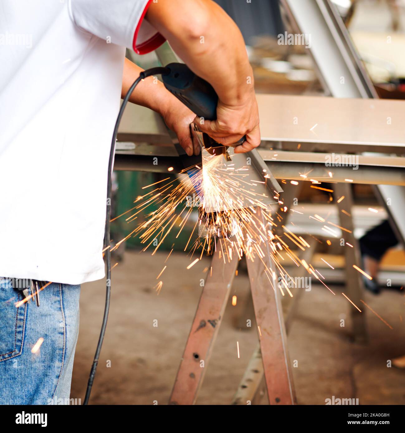 A construction worker using an angle grinder producing a lot of sparks ...