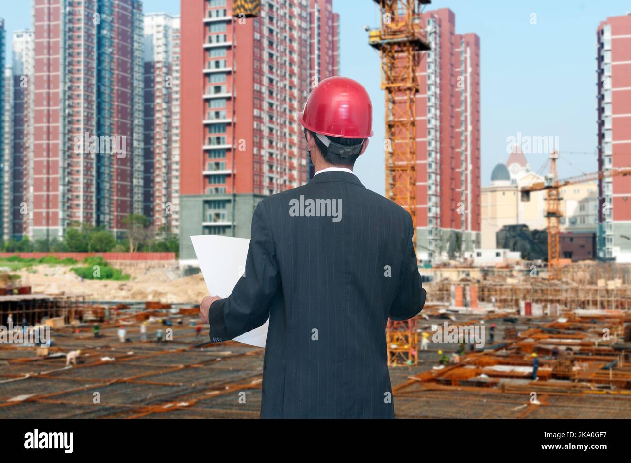 Rear view of architect looking comparing housing project with building ...