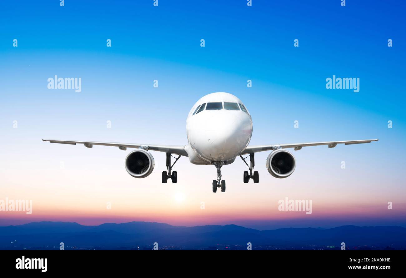 passenger plane fly down over take-off runway from airport at sunset ...