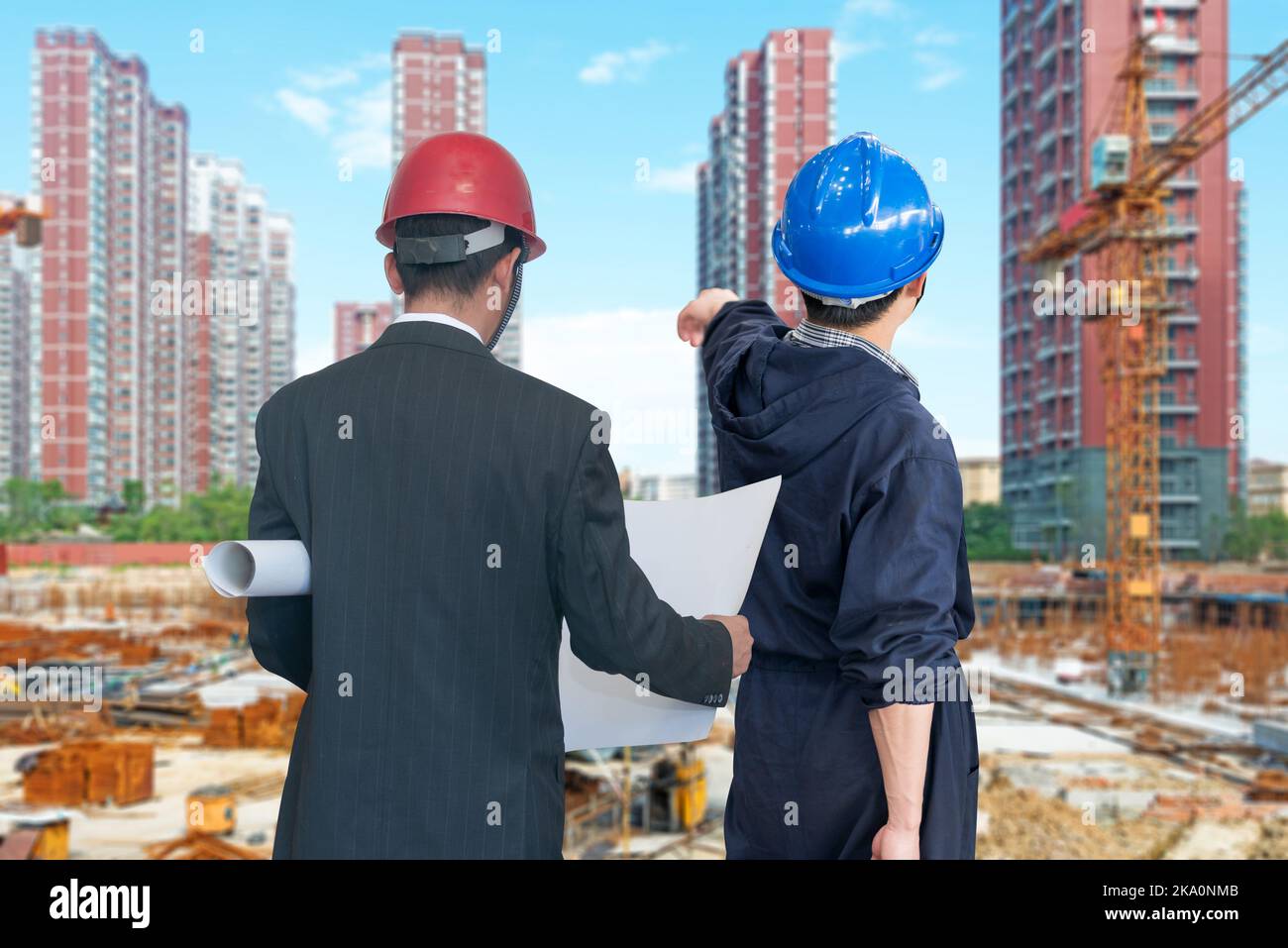 Rear view of architect looking comparing housing project with building ...