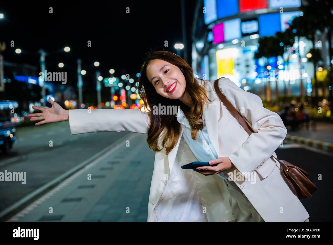 Asian business woman walking to hail waving hand taxi on road in city ...
