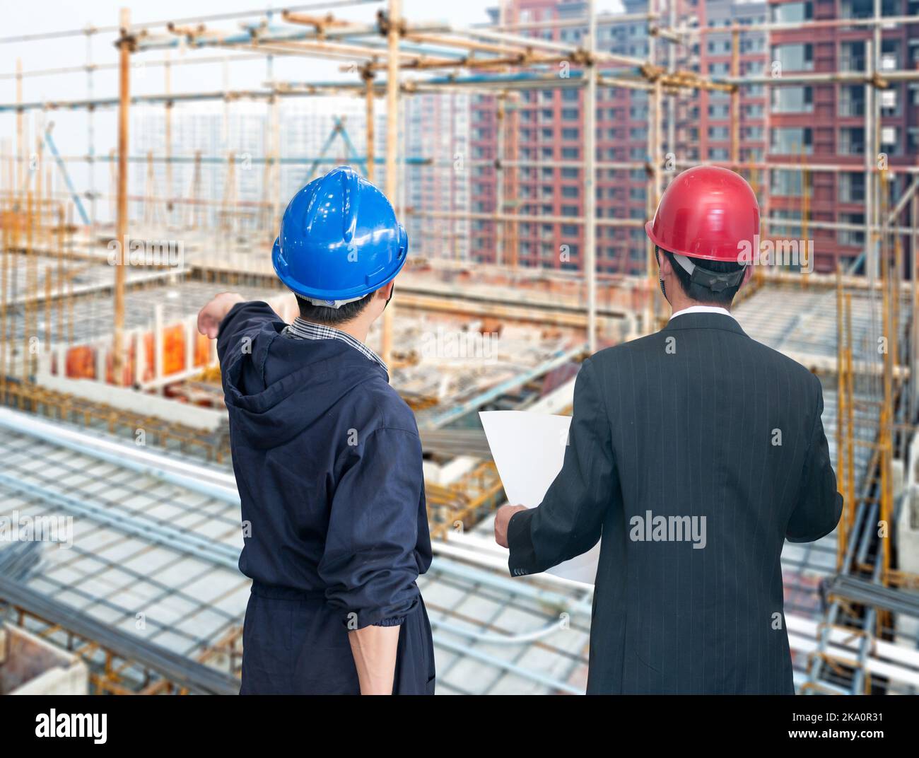 Rear view of architect looking comparing housing project with building ...