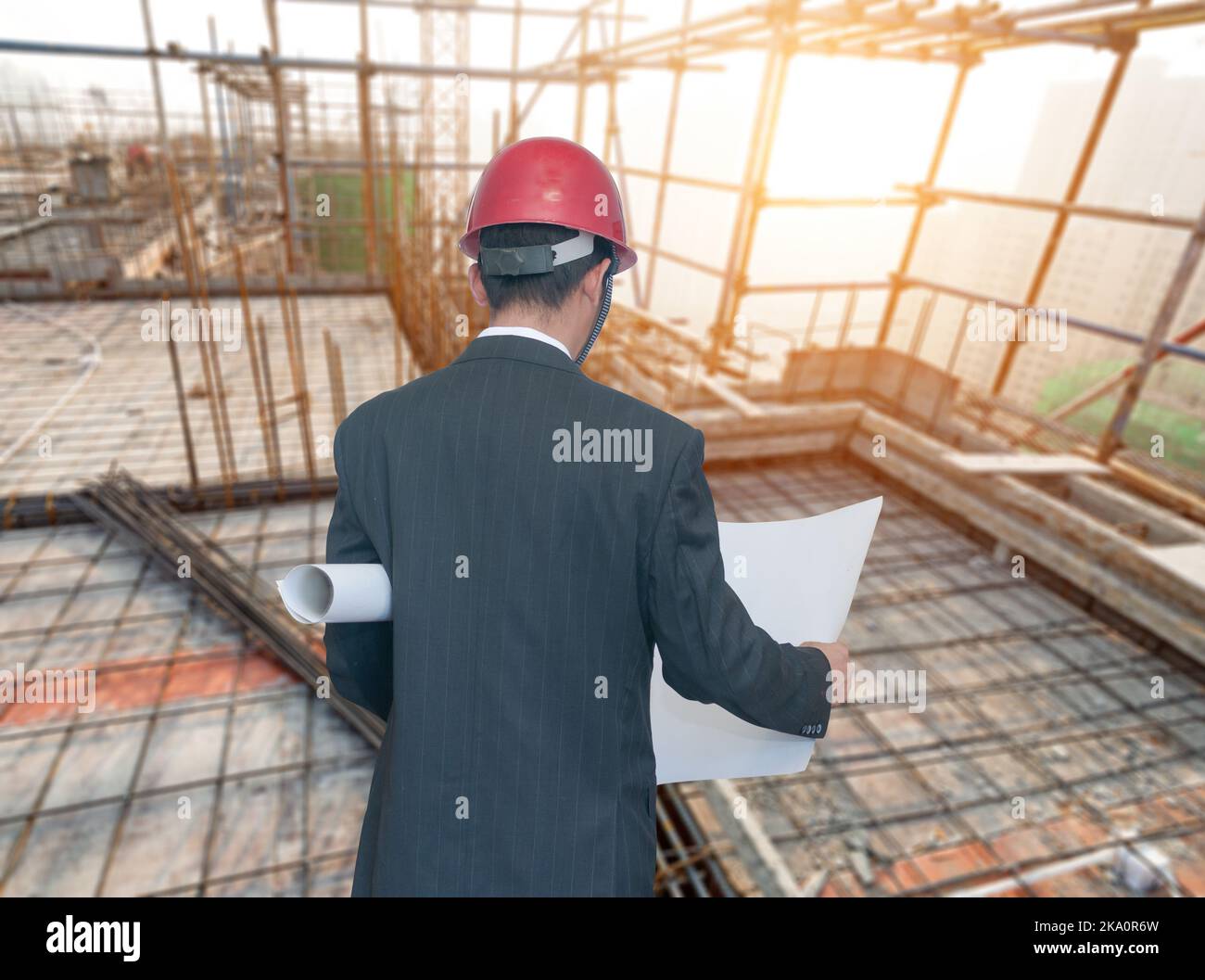 Rear view of architect looking comparing housing project with building ...