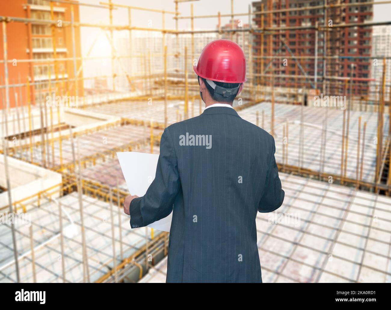 Rear view of architect looking comparing housing project with building ...