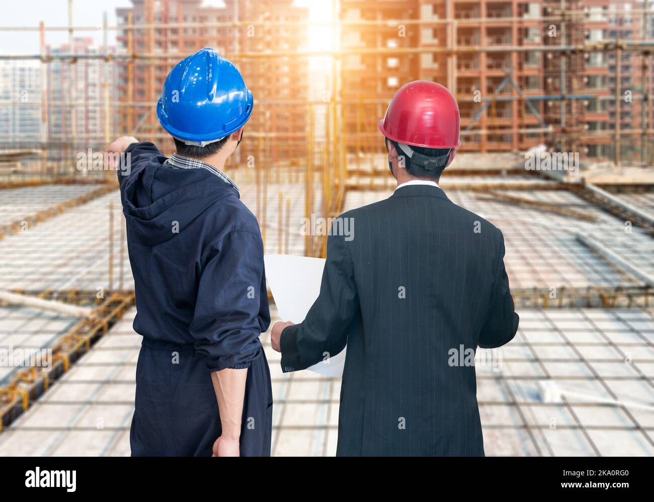 Rear view of architect looking comparing housing project with building ...