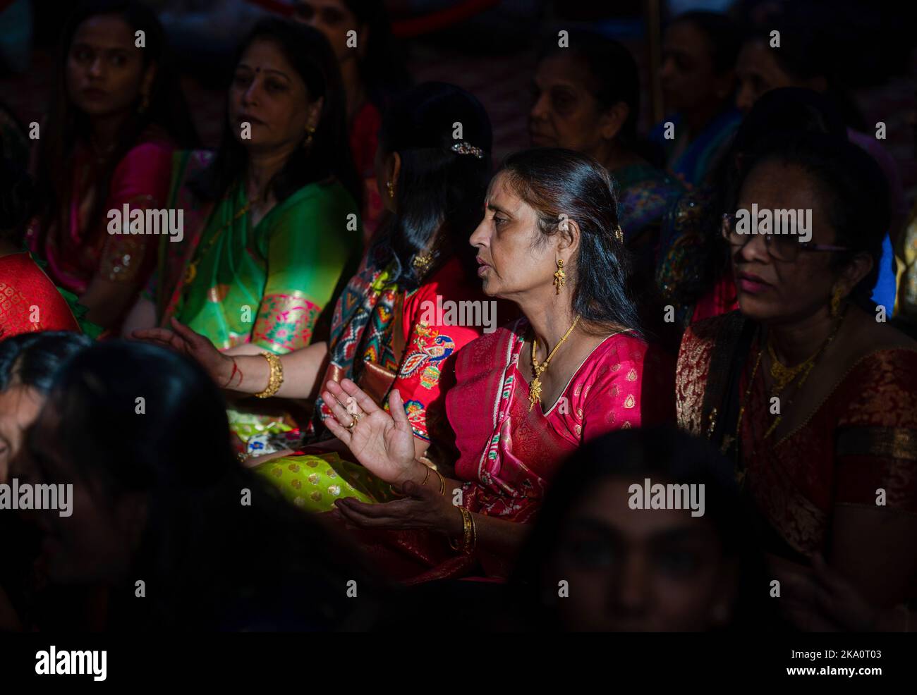 Light is cast on a woman singing and clapping during a Diwali ...