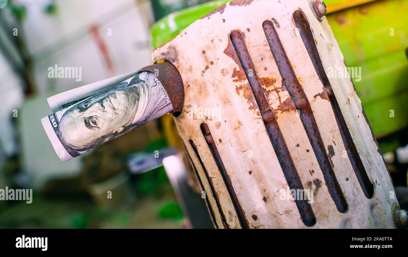 A hundred dollar bill rolled into a tube sticks out of the exhaust pipe ...