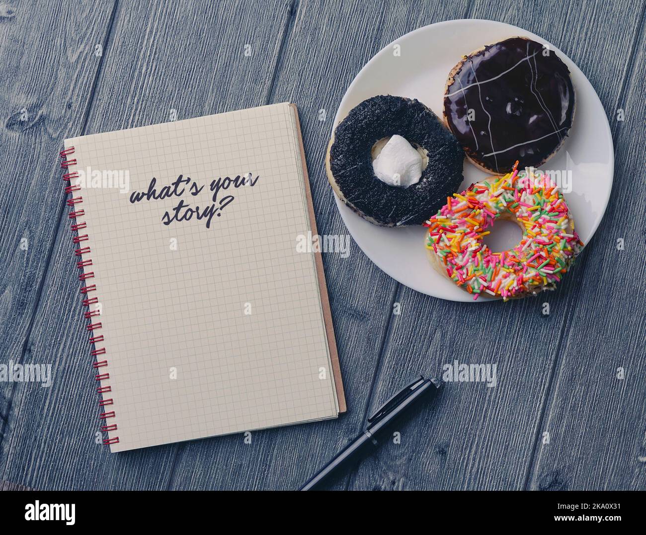 Top view of Notebook, ballpen, and doughnut on wooden background with ...