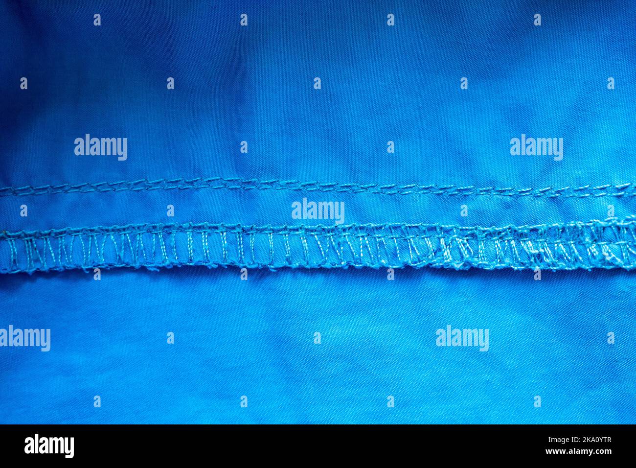 Overlock seam on blue fabric. Textured cloth background. Place for text ...