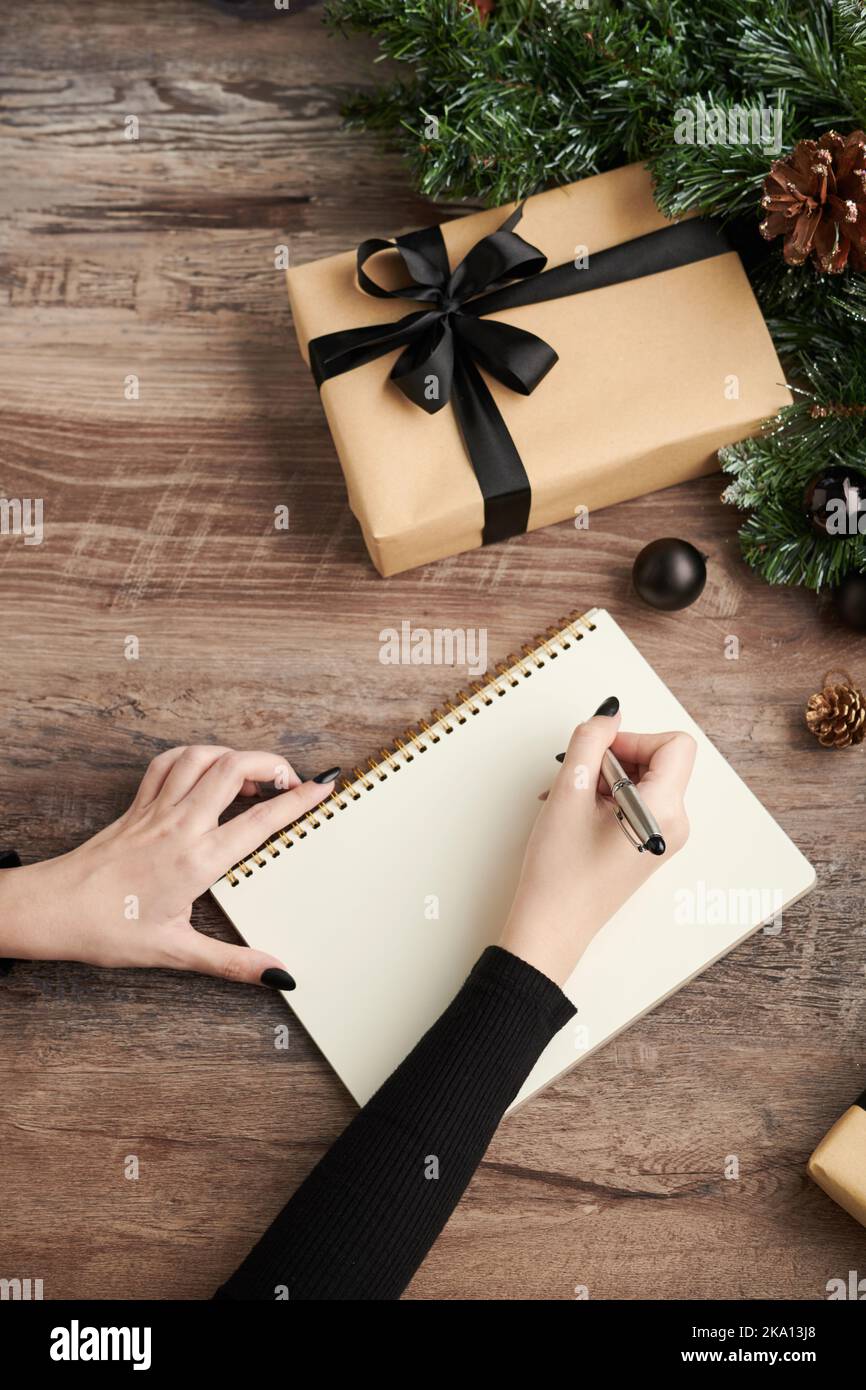 Closeup image of woman writing letter to attach to Christmas gift Stock ...