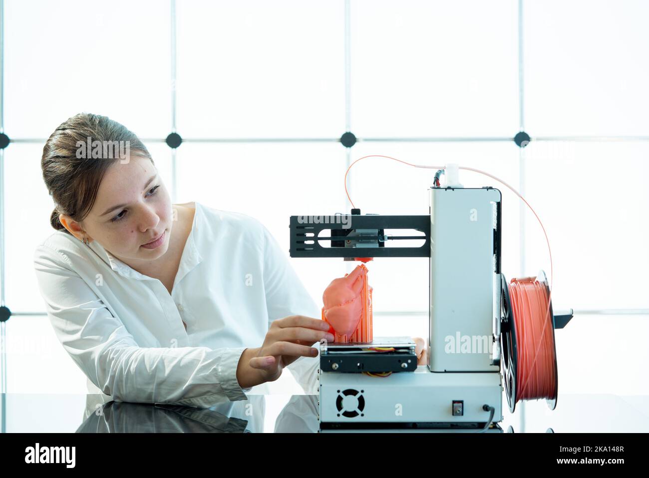 young woman student prints a model of the anatomical human heart on a ...