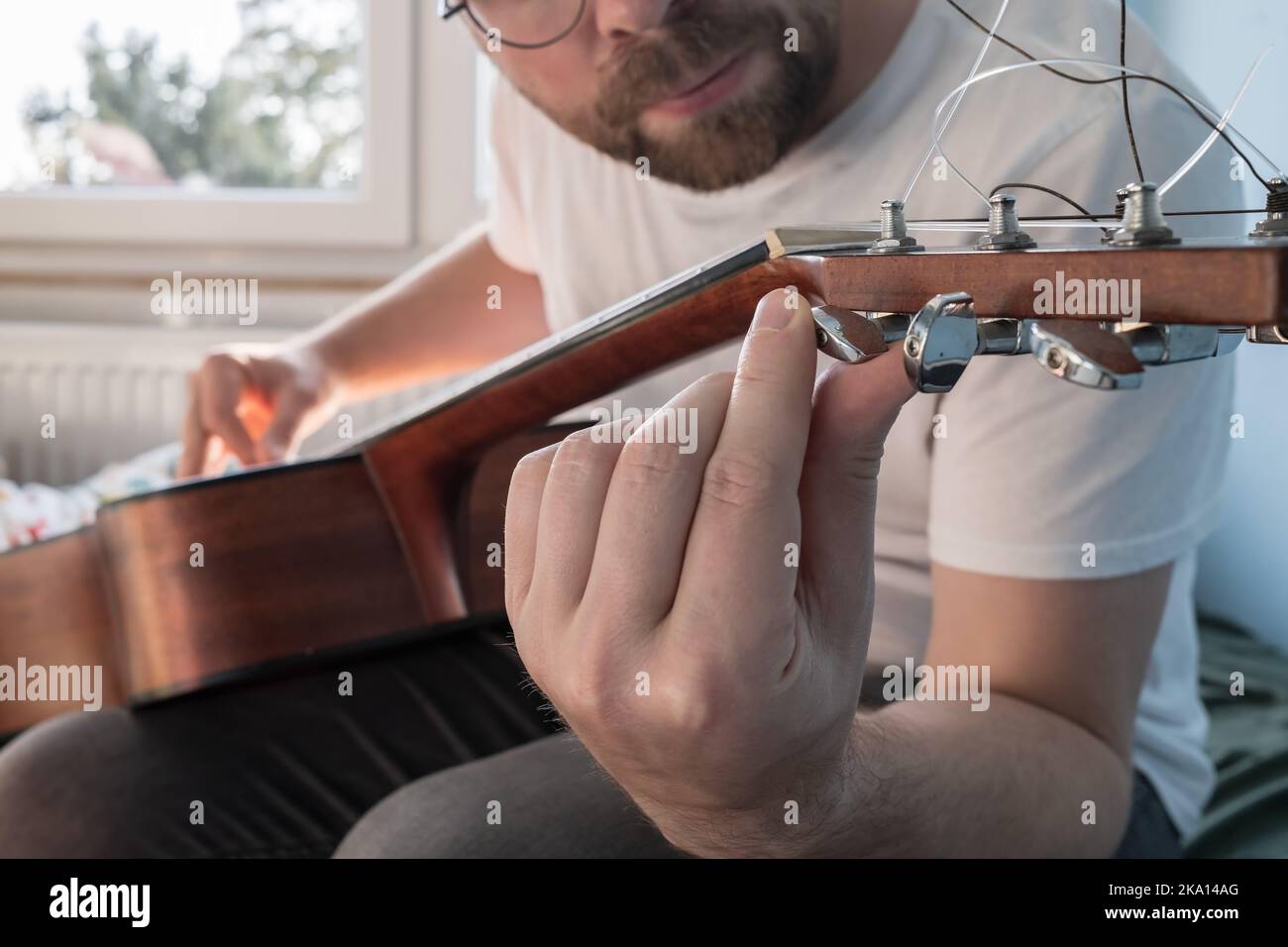 Acoustic guitar tuning. Focused man repairs a stringed musical ...