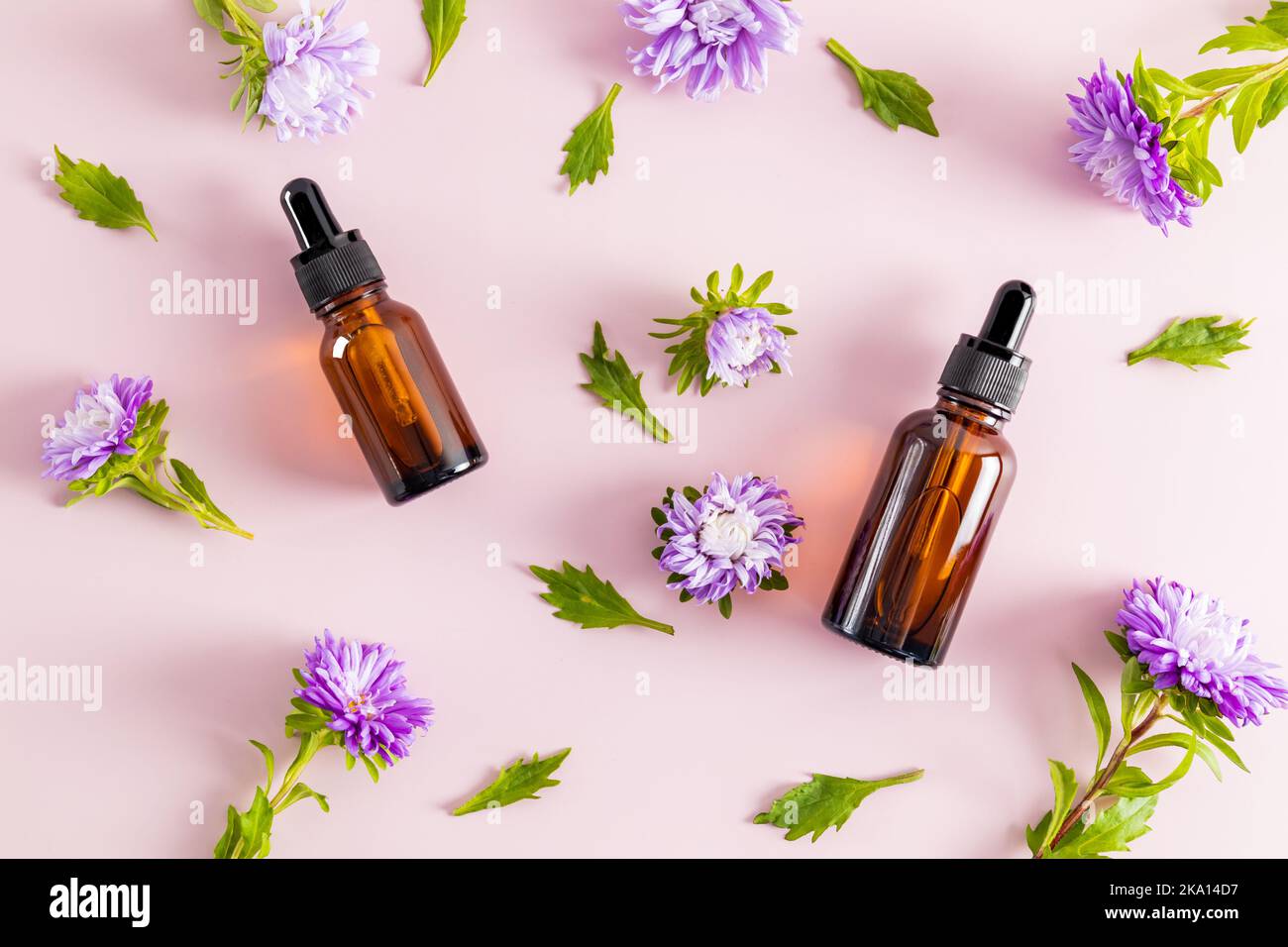 two glass dropper bottles for cosmetic use and purple flowers on a ...