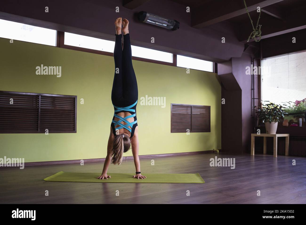 Woman in sportswear practicing yoga doing Adho Mukha Vrikshasana ...