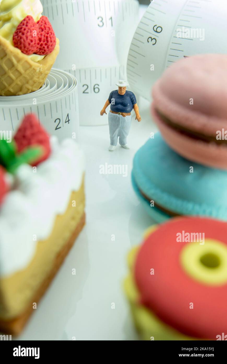miniature figure of an obese man against measuring tape and unhealthy ...