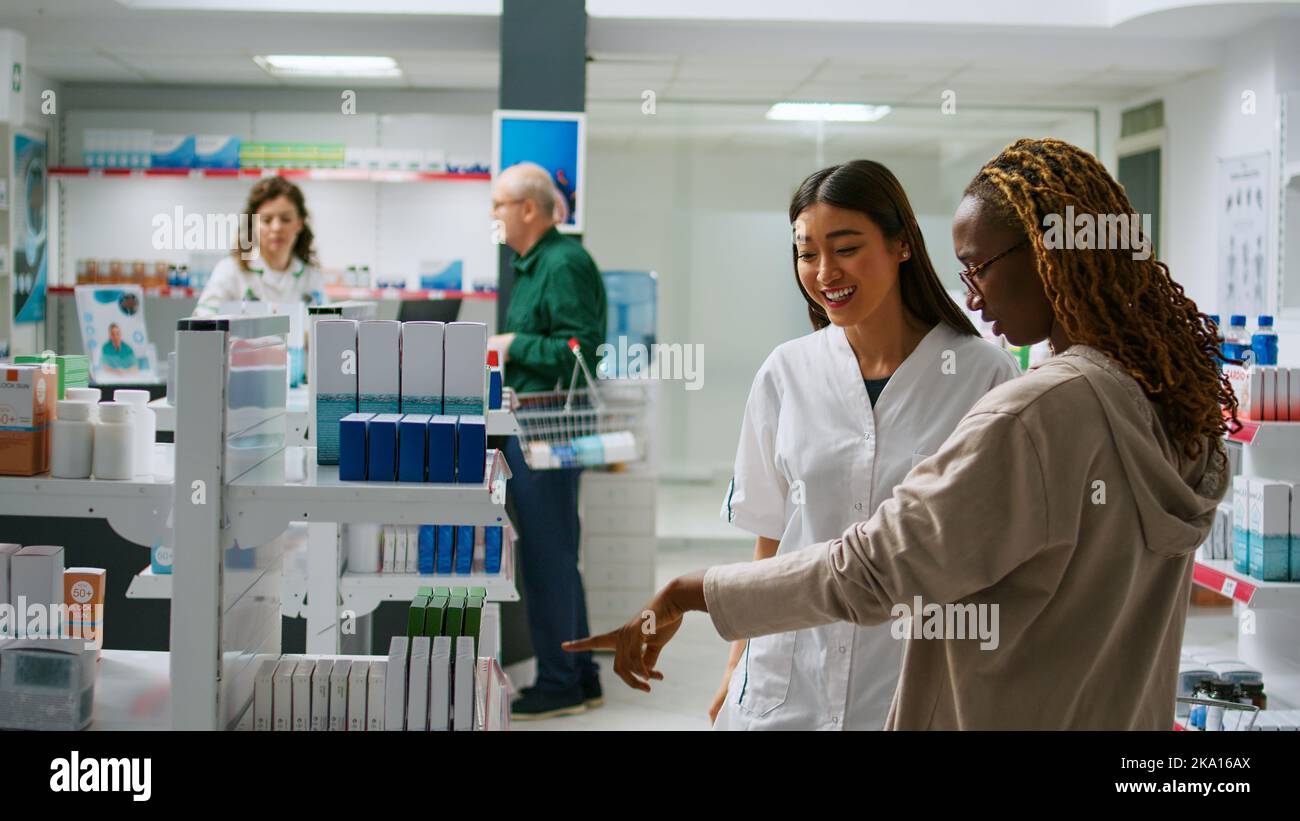 Asian pharmacist talking to diverse customers with disease, giving ...