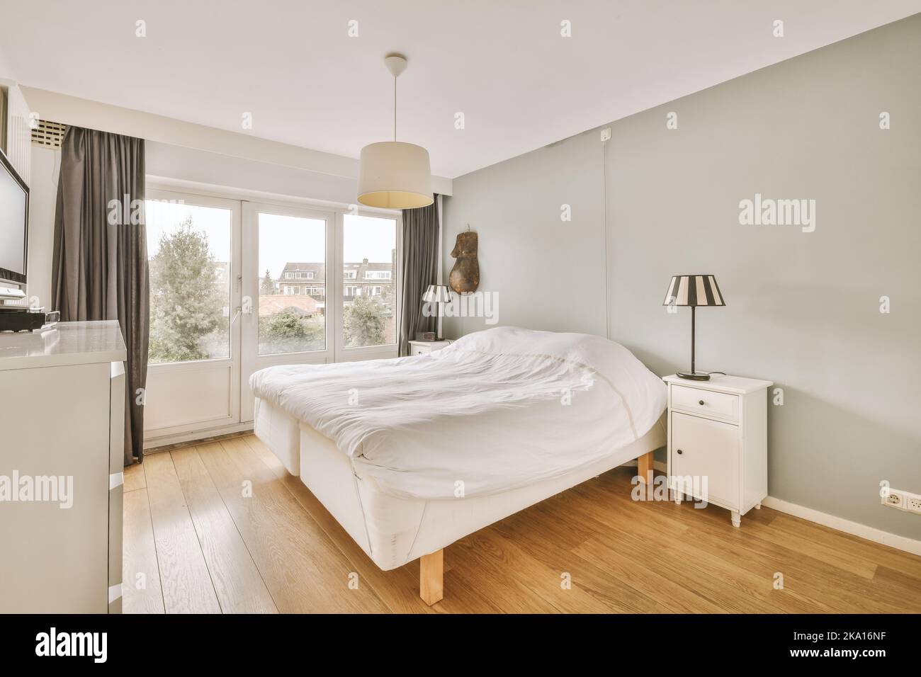 Retro bedside table with lamp located near comfortable bed and shelf ...