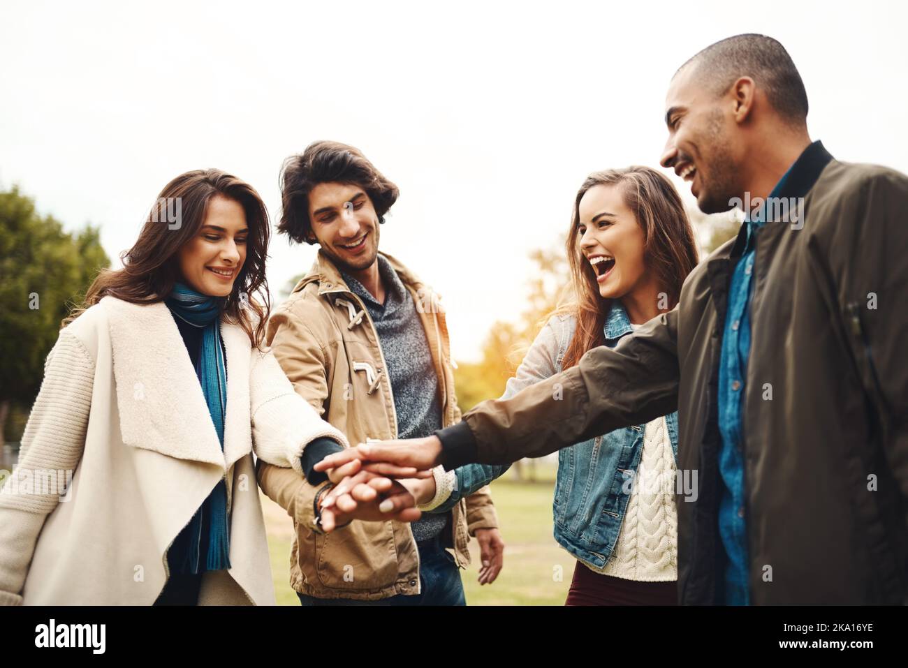 On the count of three. a group of cheerful young friends forming a ...