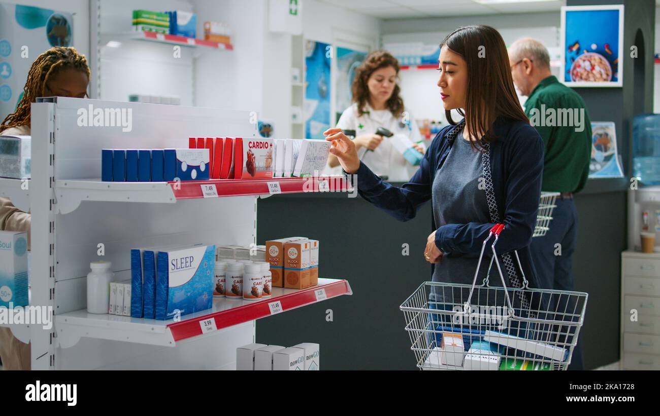 Asian client looking at medicine boxes and pills bottles on shelves ...