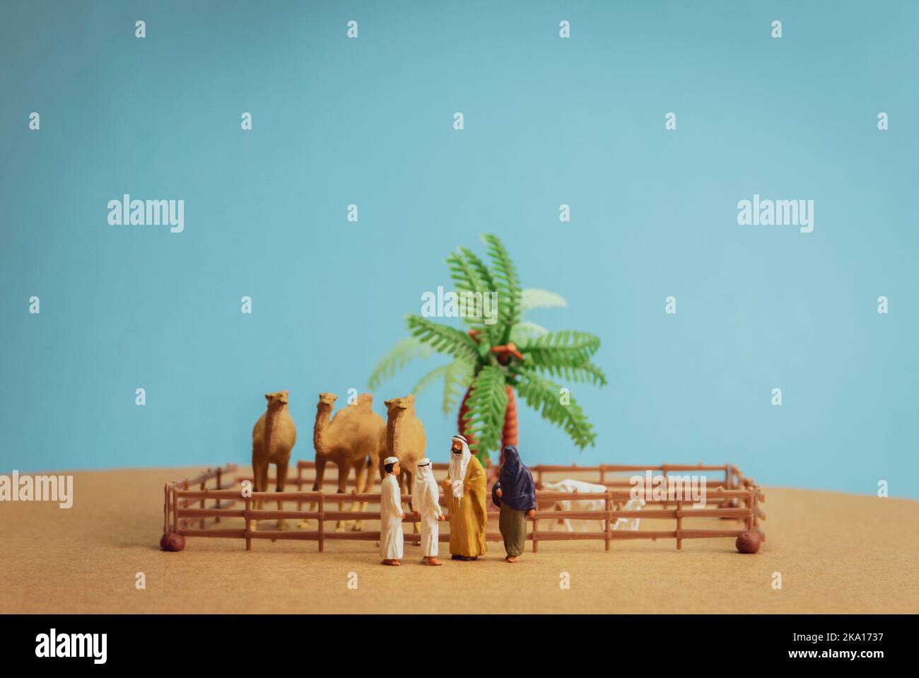 Miniature toy Arab man and wife in abaya buys camel and sheep from a ...