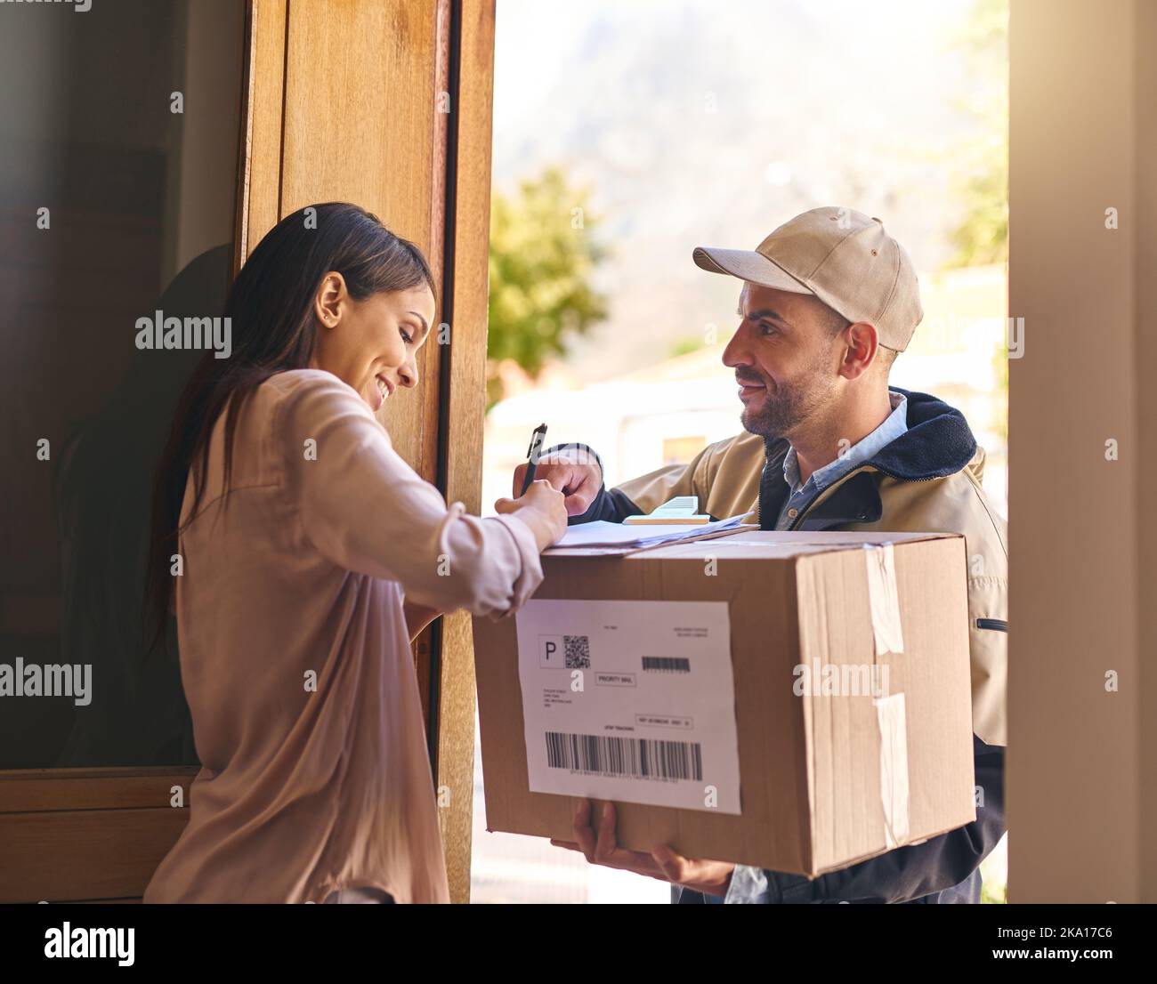 Right on the dotted line please. a young woman signing for her delivery ...