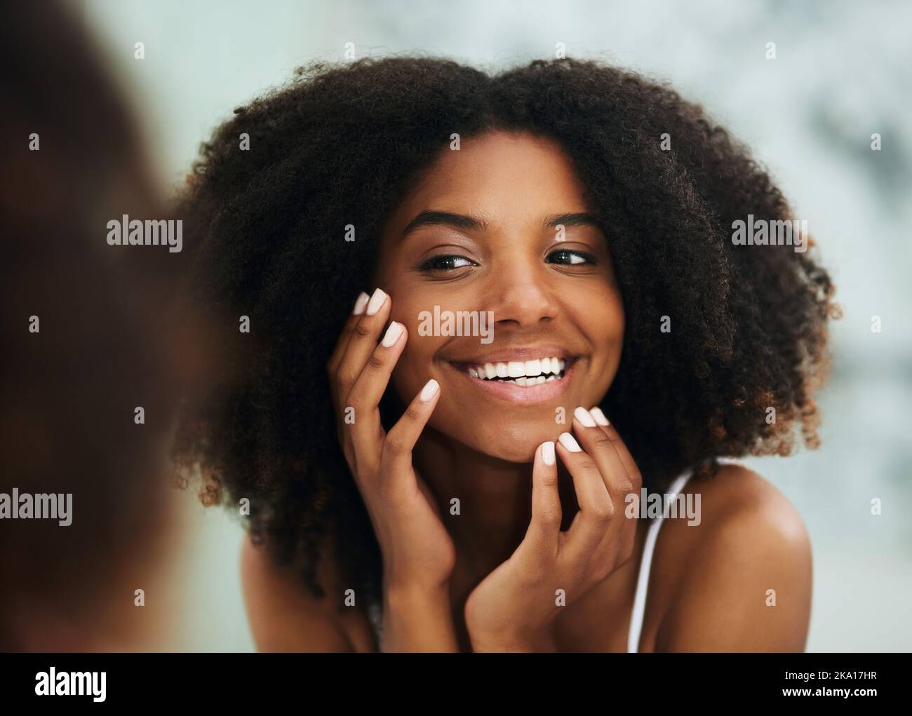 Loving my smooth, glowing skin. an attractive young woman looking at ...