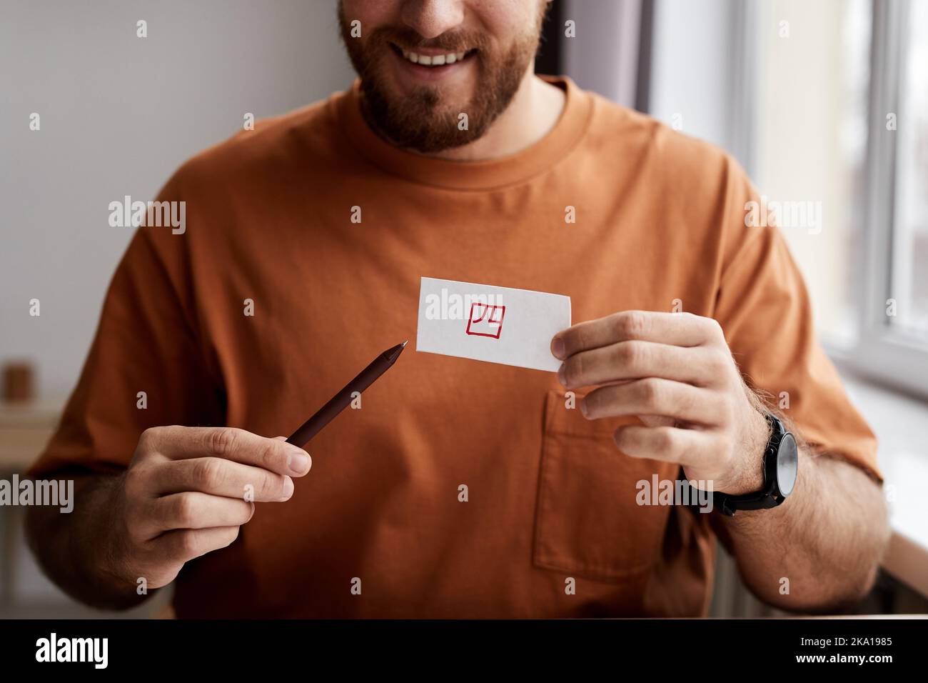 Close-up of smiling young man showing paper card with hieroglyph ...