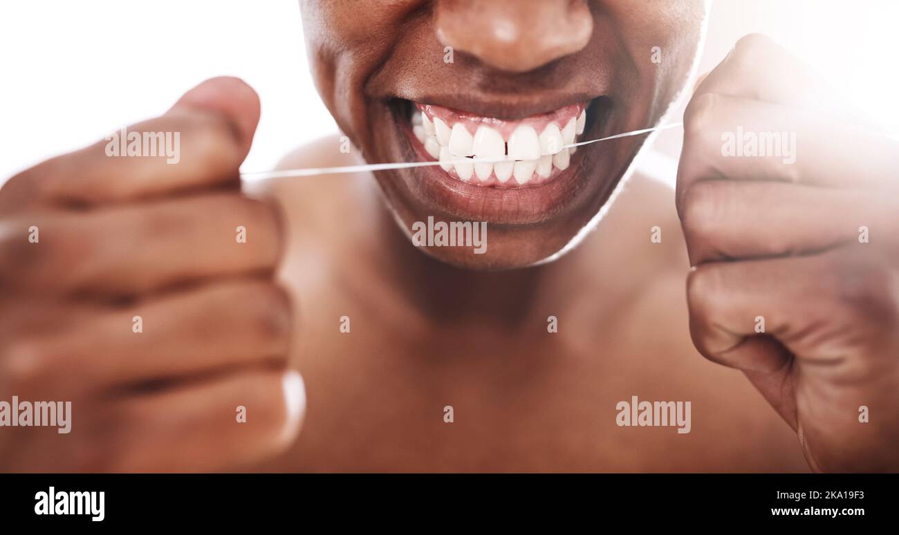 Always remember to floss regularly. an unrecognizable young man flossing his teeth in the ...