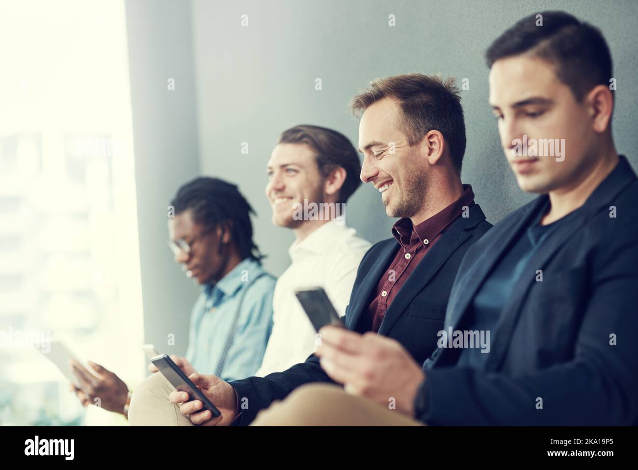 Catching up on texts while we wait. a group of businessmen using ...