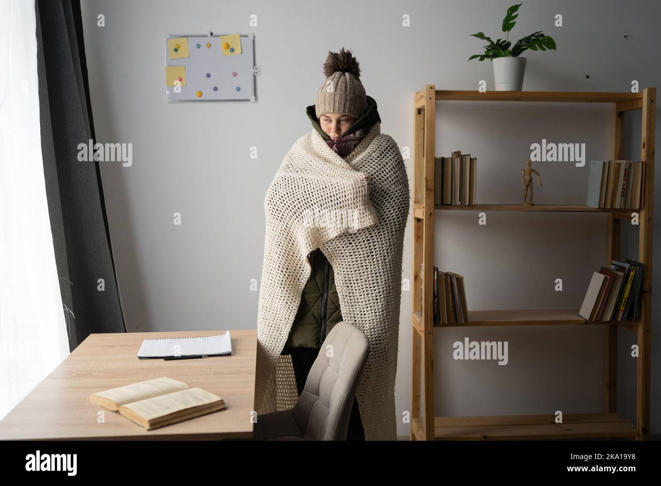 Angry girl student warmly dressed in a cold house suffering from cold ...
