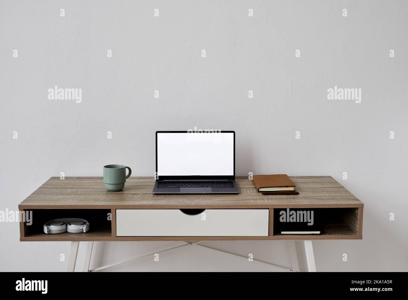 Front view of laptop with blank screen standing between cup and ...