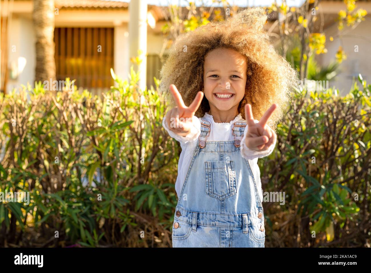 Cheerful preteen African American girl with curly hair showing two ... Cheerful preteen African American girl with curly hair showing two ...