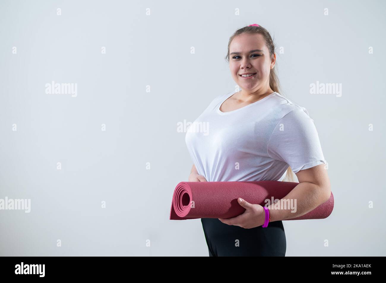 Young fat caucasian woman holding a sport mat. Charming plus size model ...