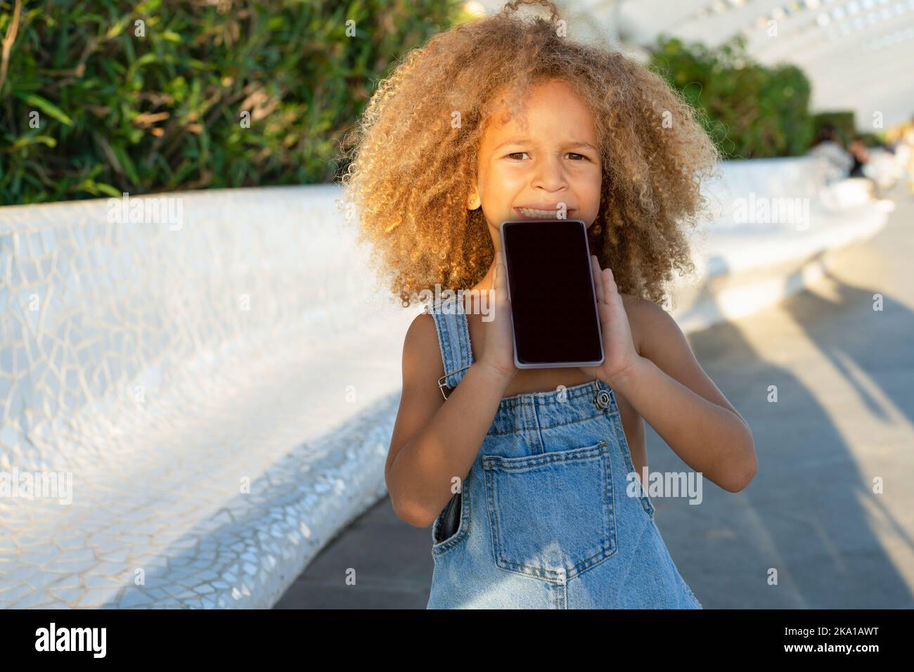 Child is using mobile phone. Kid is smiling and looking at screen of ...