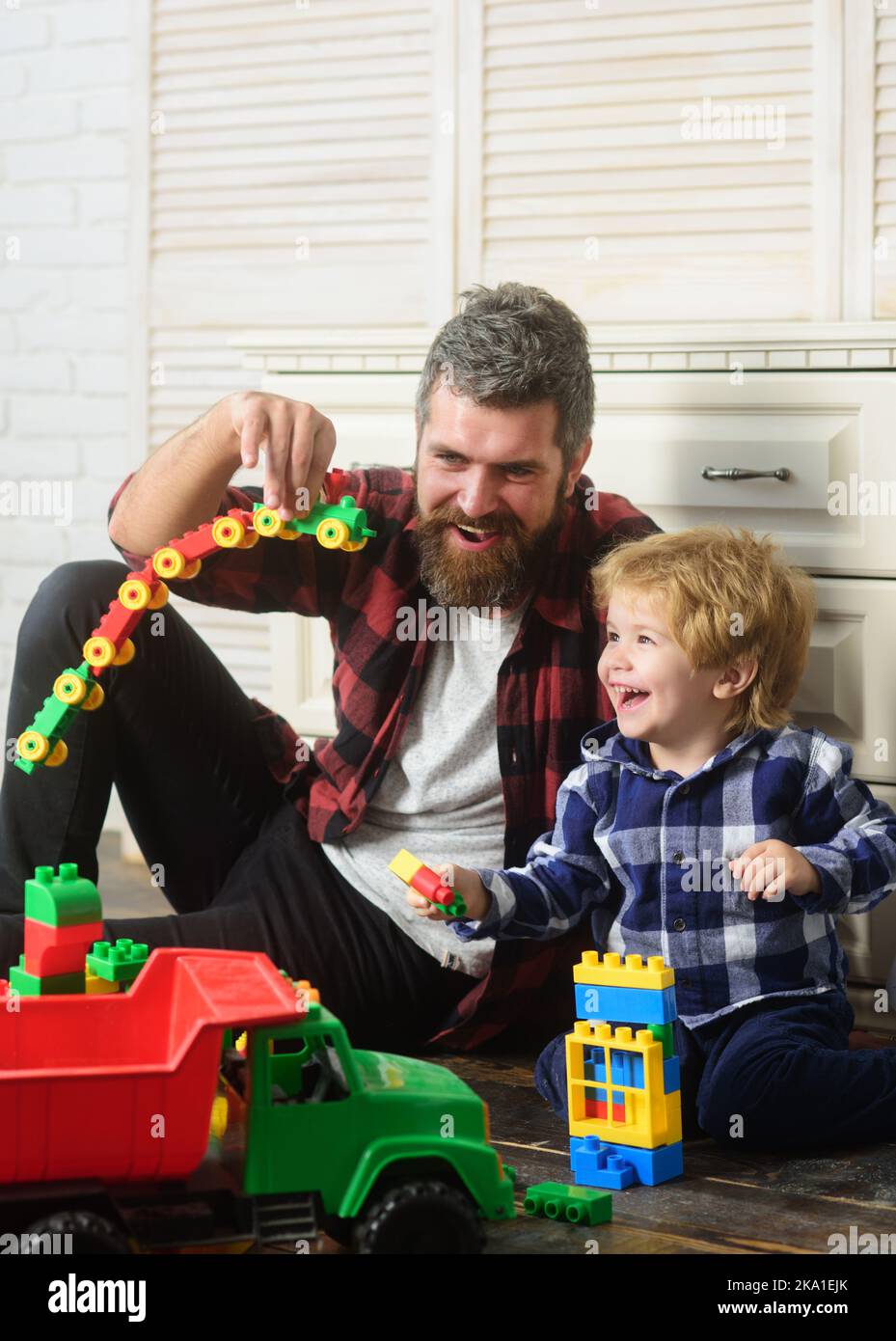 Father and son create toys from bricks. Dad and kid build of plastic ...