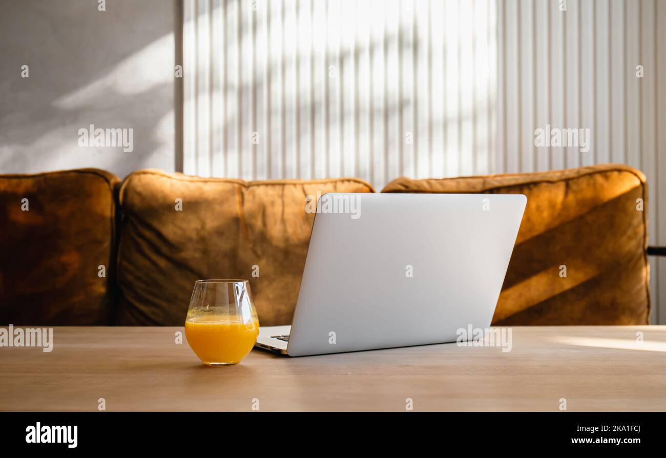 A glass of orange juice near the laptop on the table Stock Photo - Alamy