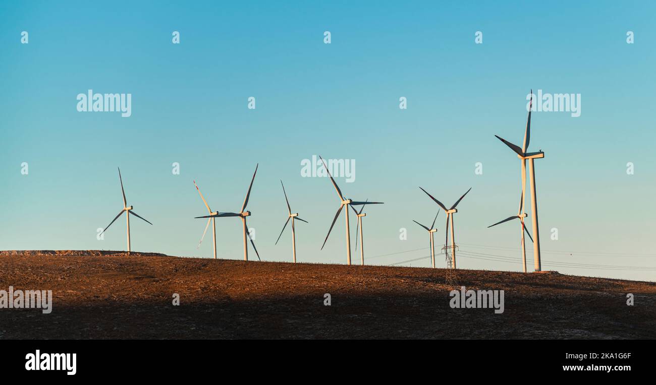 Multiple wind turbines standing on a hill at sunrise and generating ...